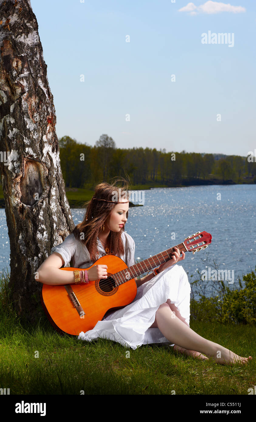 outdoor portrait of beautiful hippie girl sitting near birch with ...