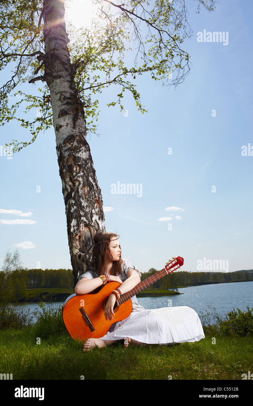 outdoor portrait of beautiful hippie girl sitting on green grass near ...