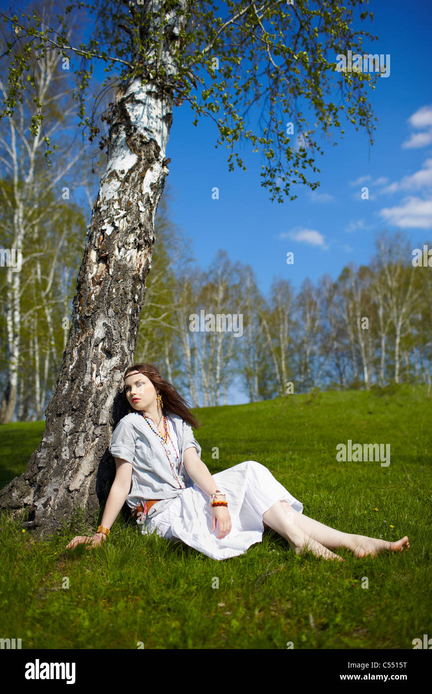 outdoor portrait of beautiful hippie girl sitting on green grass near ...