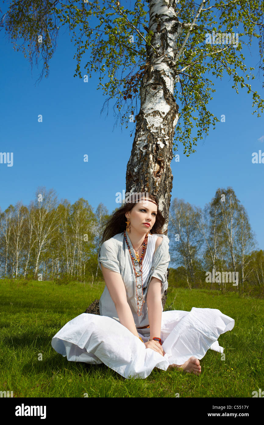 outdoor portrait of beautiful hippie girl sitting on green grass near ...