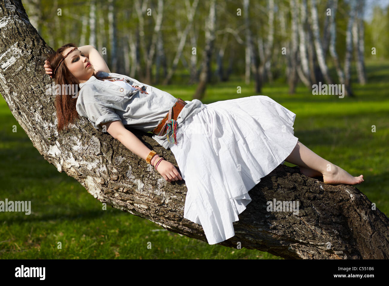 outdoor portrait of beautiful hippie girl lying on birch tree. forest ...