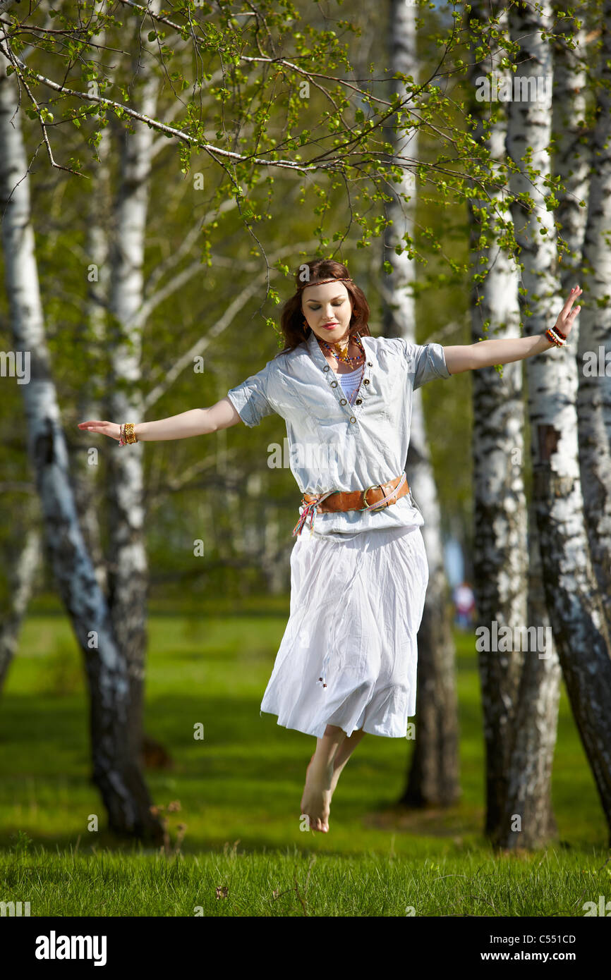 outdoor portrait of beautiful hippie girl jumping on green grass in ...