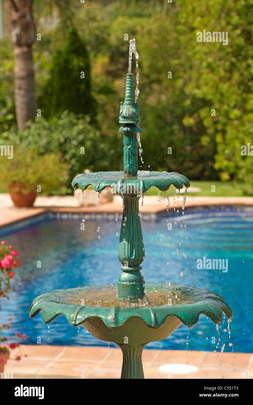 Classic small fountain splashing in a garden with large pool Stock ...