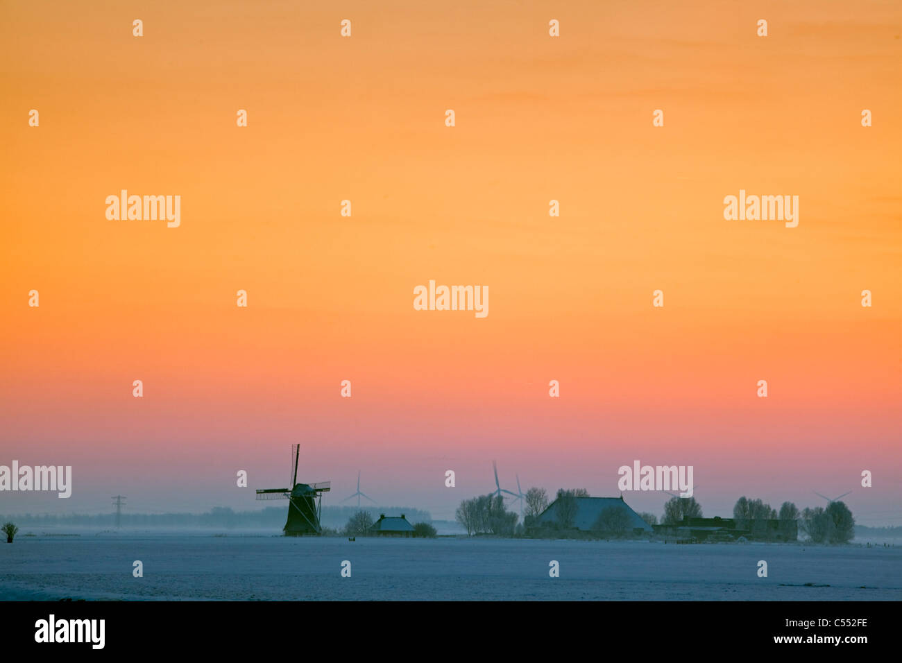 The Netherlands, Tritzum, Windmill and farm in snow at sunset Stock ...