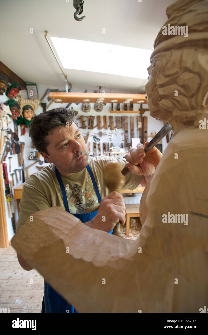 Wood carver working on a large sculpture in his workshop in Titisee ...