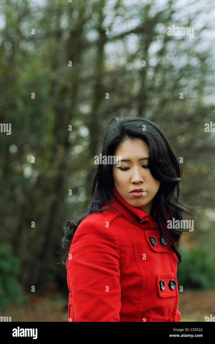 Sad young Chinese woman standing in the woods looking down Stock Photo ...