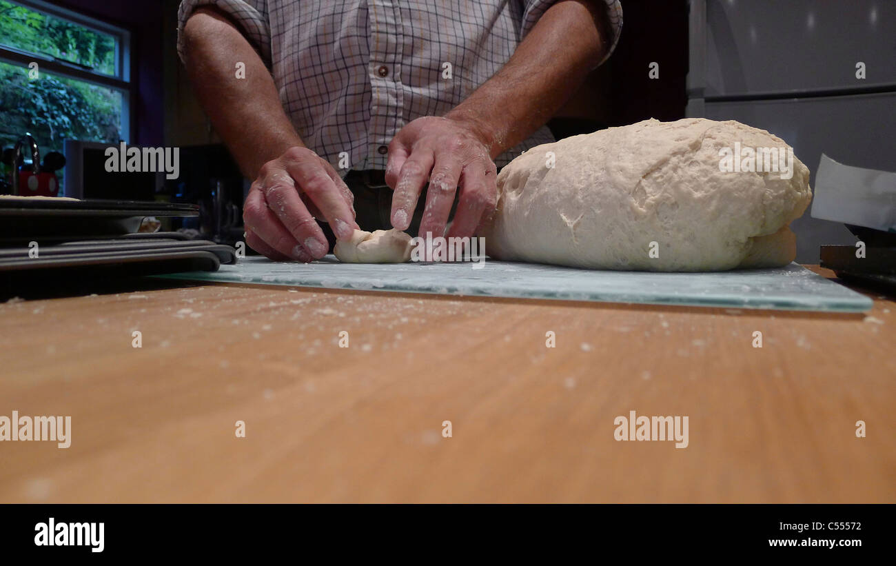 Man's hands kneading bread dough to make bread buns at kitchen counter ...
