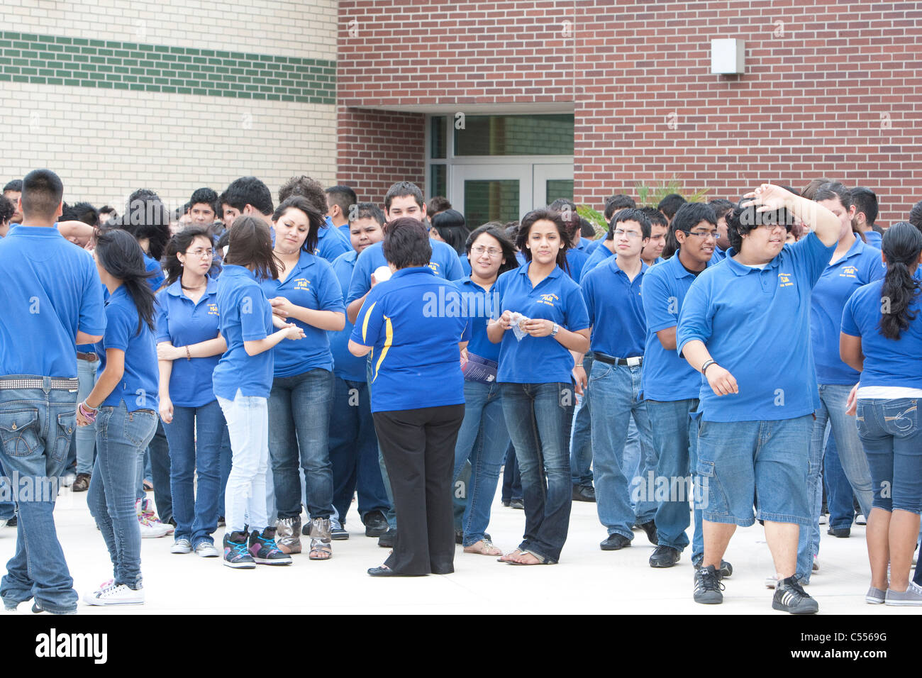 Group of male and female students wearing school uniform gather outside ...