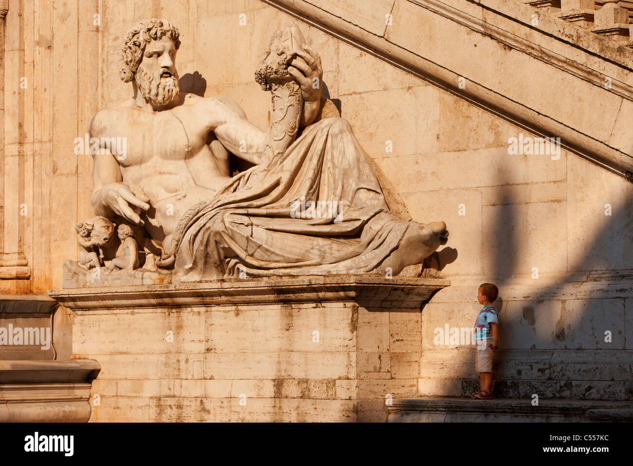 Small tourist inspects the giant reclining male sculpture inside Piazza ...