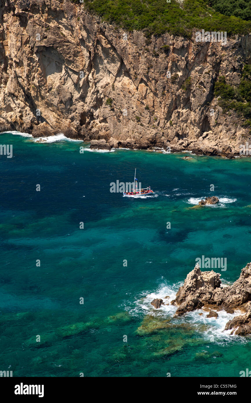 Tourist boat heads out to sea through clear blue and green water near ...
