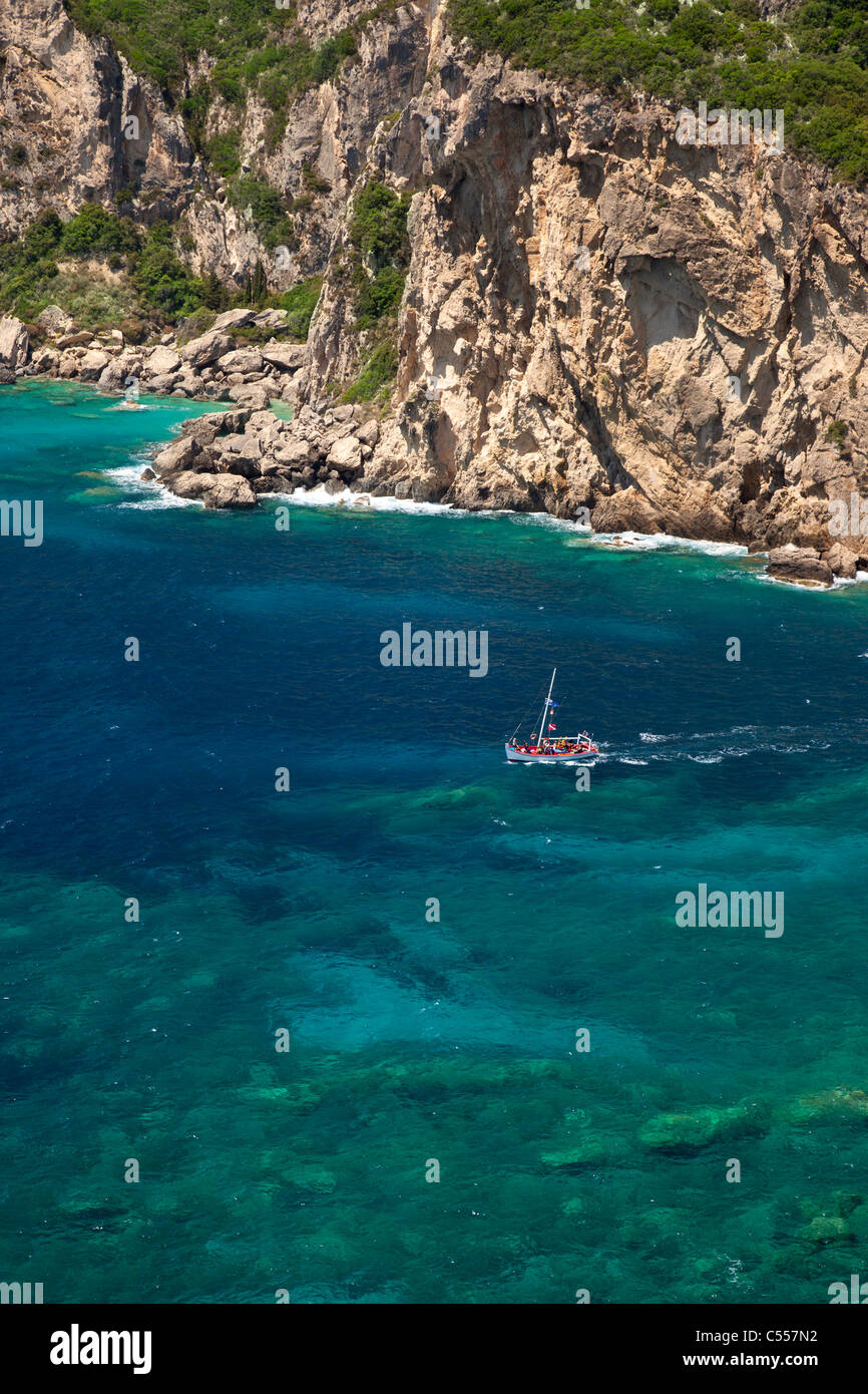 Tourist boat heads out to sea through clear blue and green water near ...
