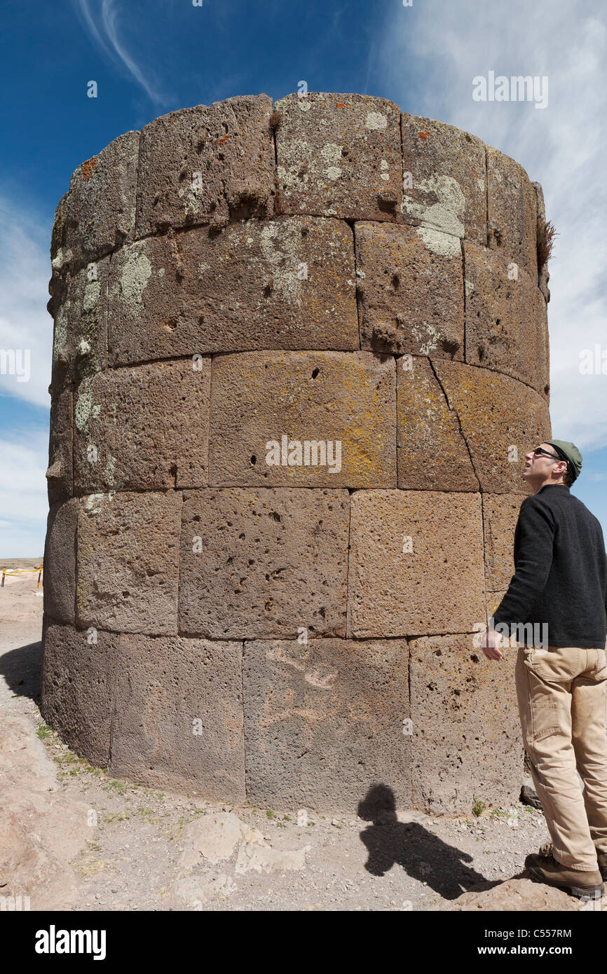 A visitor inspects one of the funerary towers or Chullpas at Silustani ...
