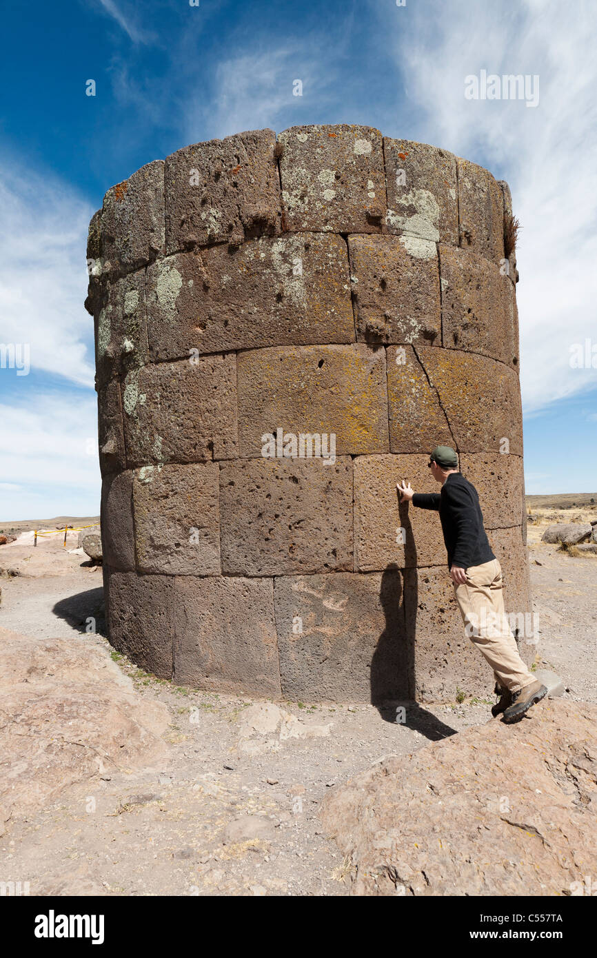 A visitor inspects one of the funerary towers or Chullpas at Silustani ...
