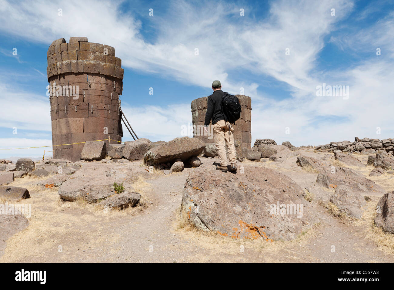 A visitor inspects one of the funerary towers or Chullpas at Silustani ...