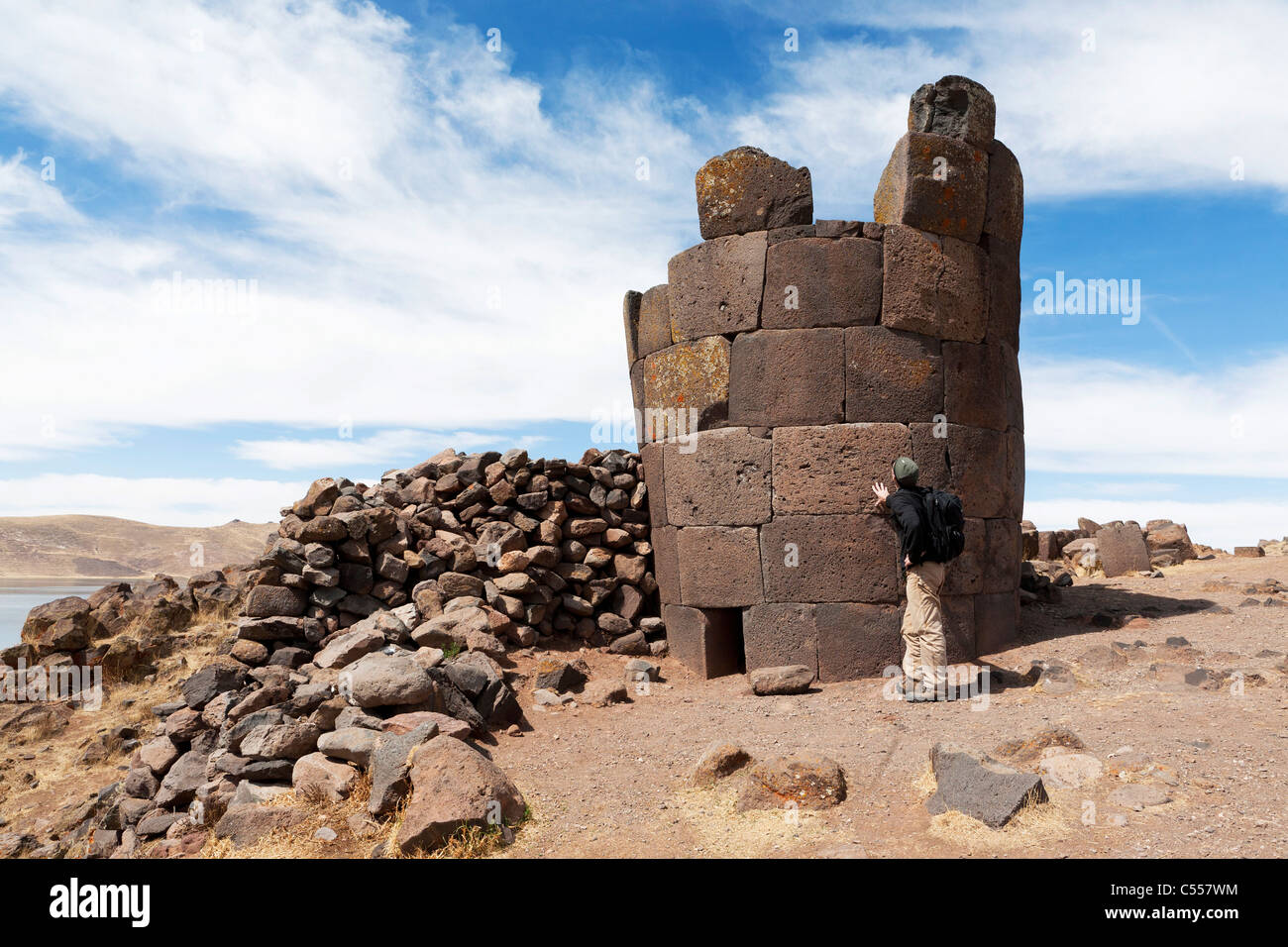 A visitor inspects one of the funerary towers or Chullpas at Silustani ...