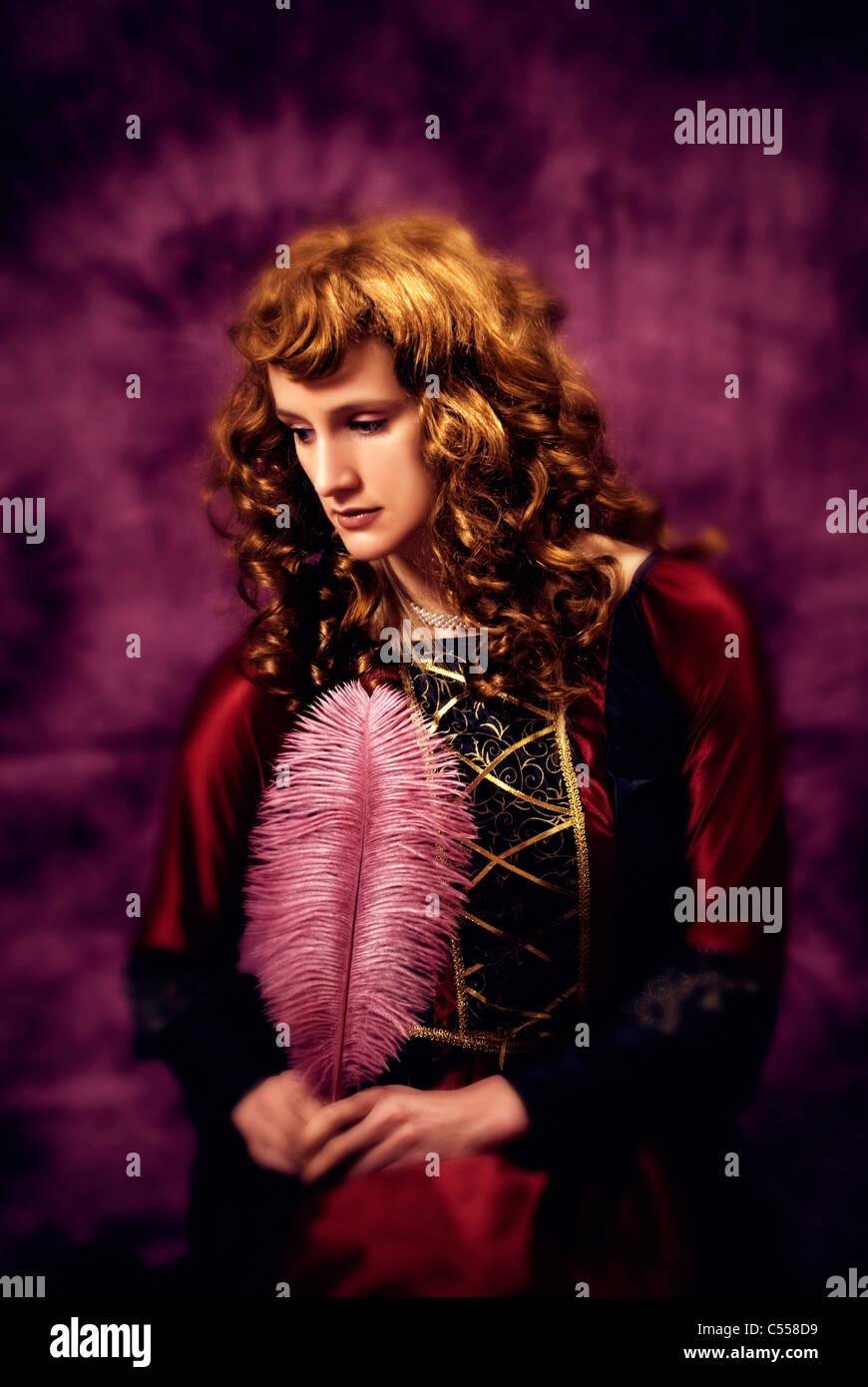 Sad medieval woman holding a pink feather Stock Photo - Alamy