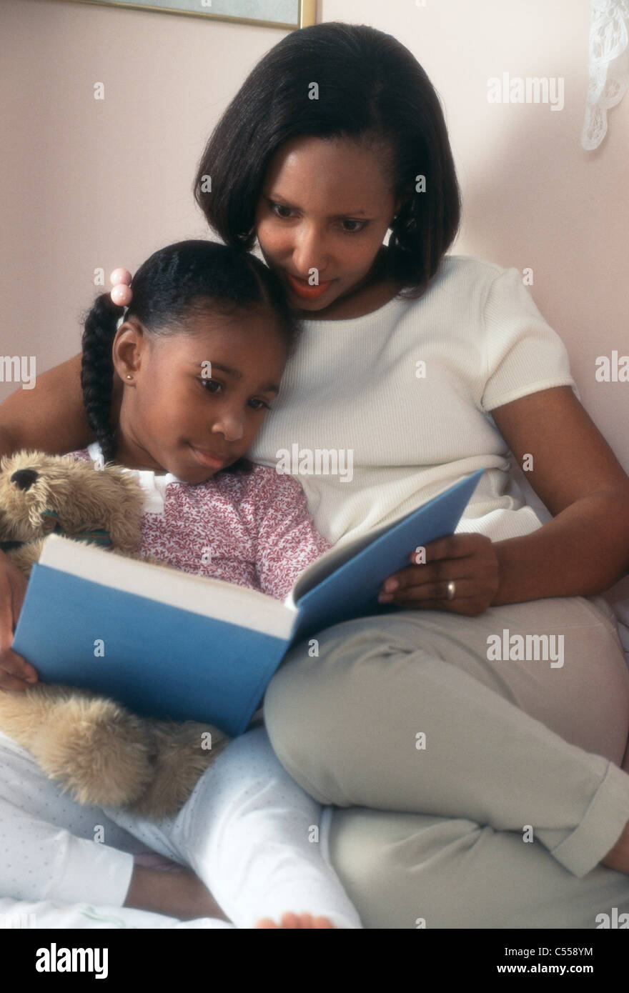 Woman and her daughter reading a book Stock Photo - Alamy