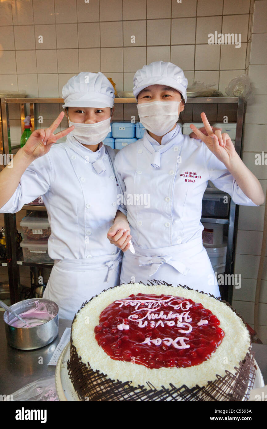 Female chefs standing in a kitchen near a cake, Beijing, China Stock ...