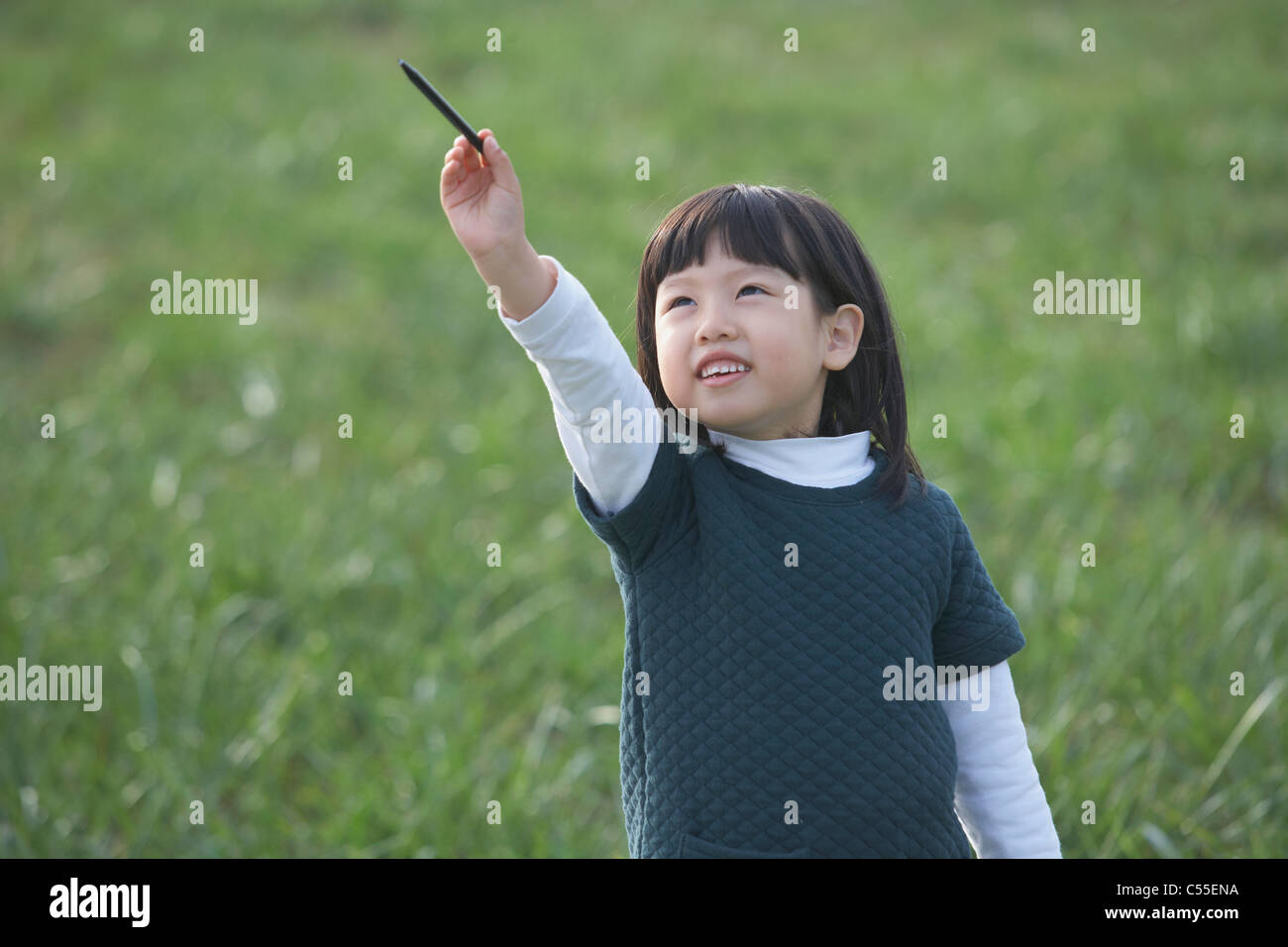A smiling girl pointing in the grass field Stock Photo - Alamy