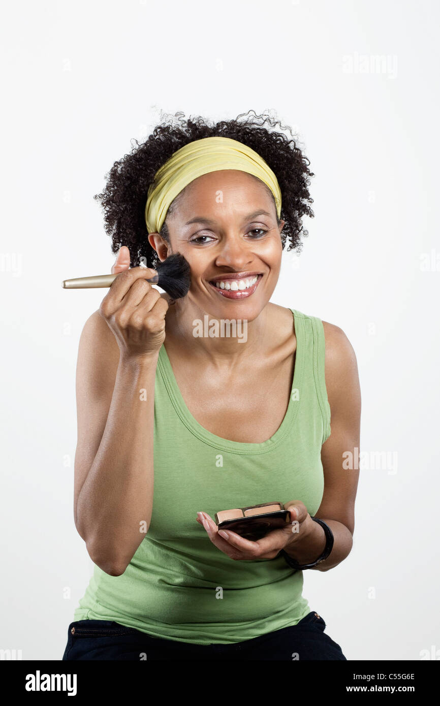 Mid adult woman applying make-up on face Stock Photo - Alamy
