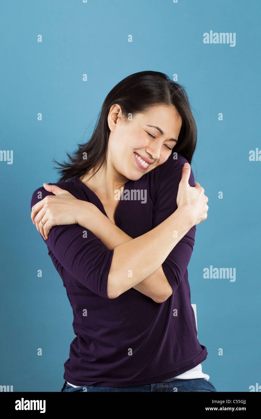 Young woman hugging herself and smiling Stock Photo - Alamy