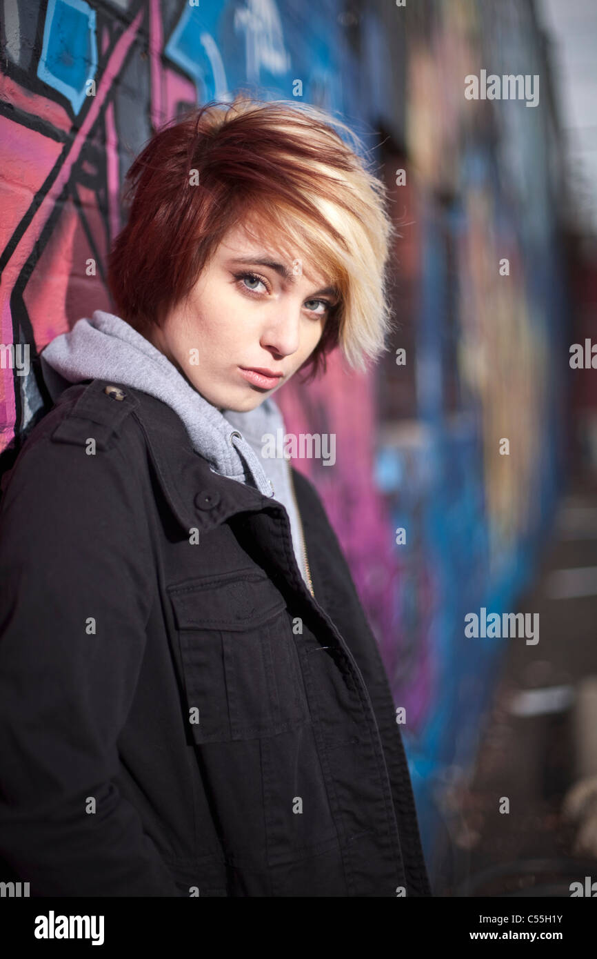 Portrait of sad punk girl standing by graffiti wall Stock Photo - Alamy