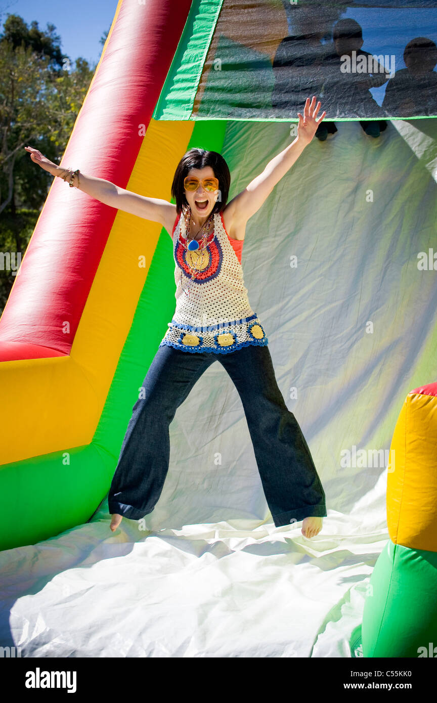 Young woman jumping on an inflatable slide Stock Photo - Alamy