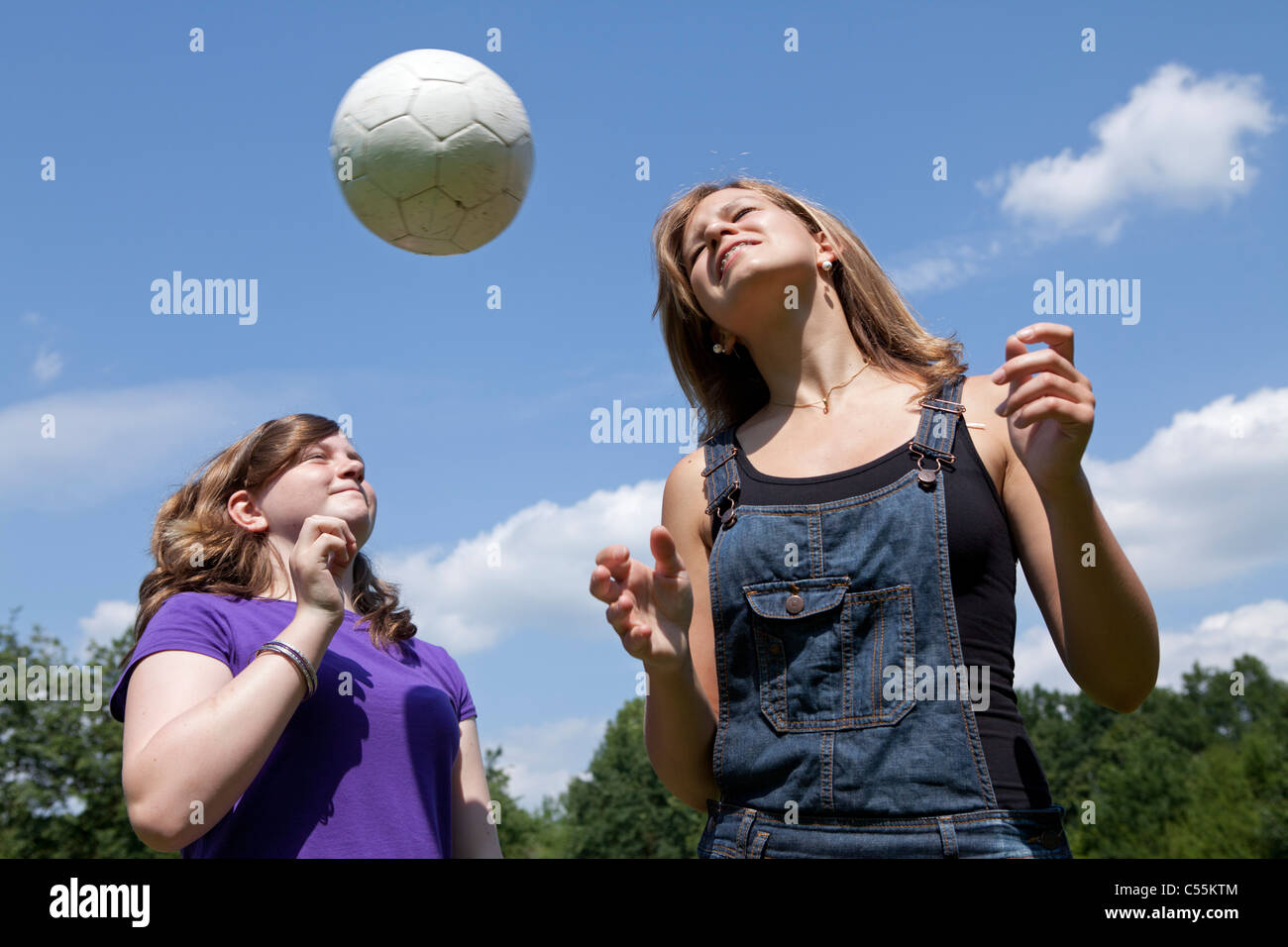two young girls trying to head a football Stock Photo - Alamy