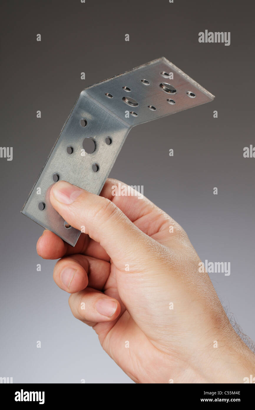 Man holding a 90° metallic angle bracket in his hand Stock Photo - Alamy
