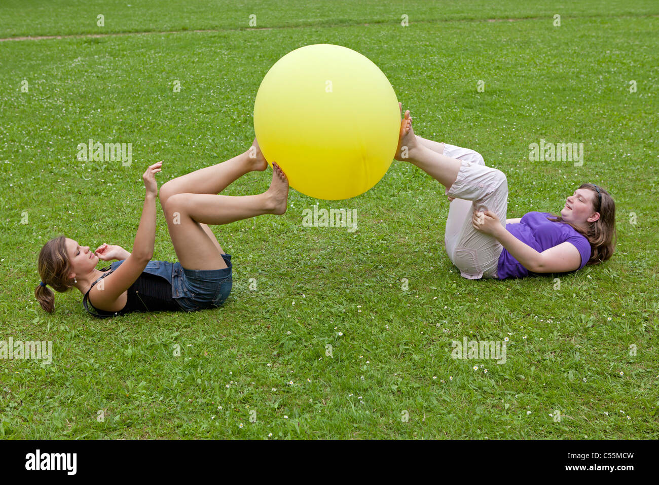 two young girls balancing a big balloon between their feet Stock Photo ...