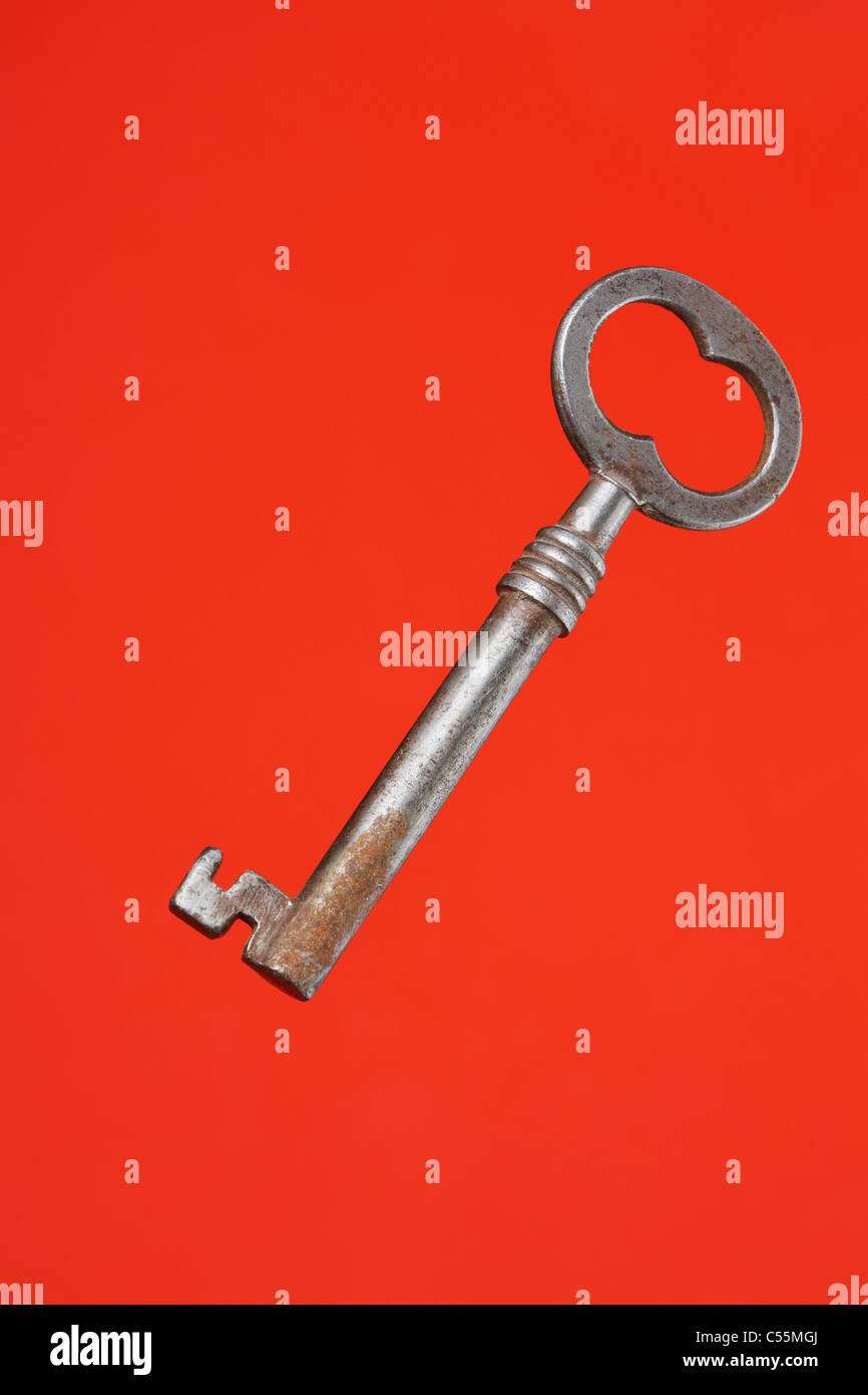 Old metallic key on red background Stock Photo - Alamy