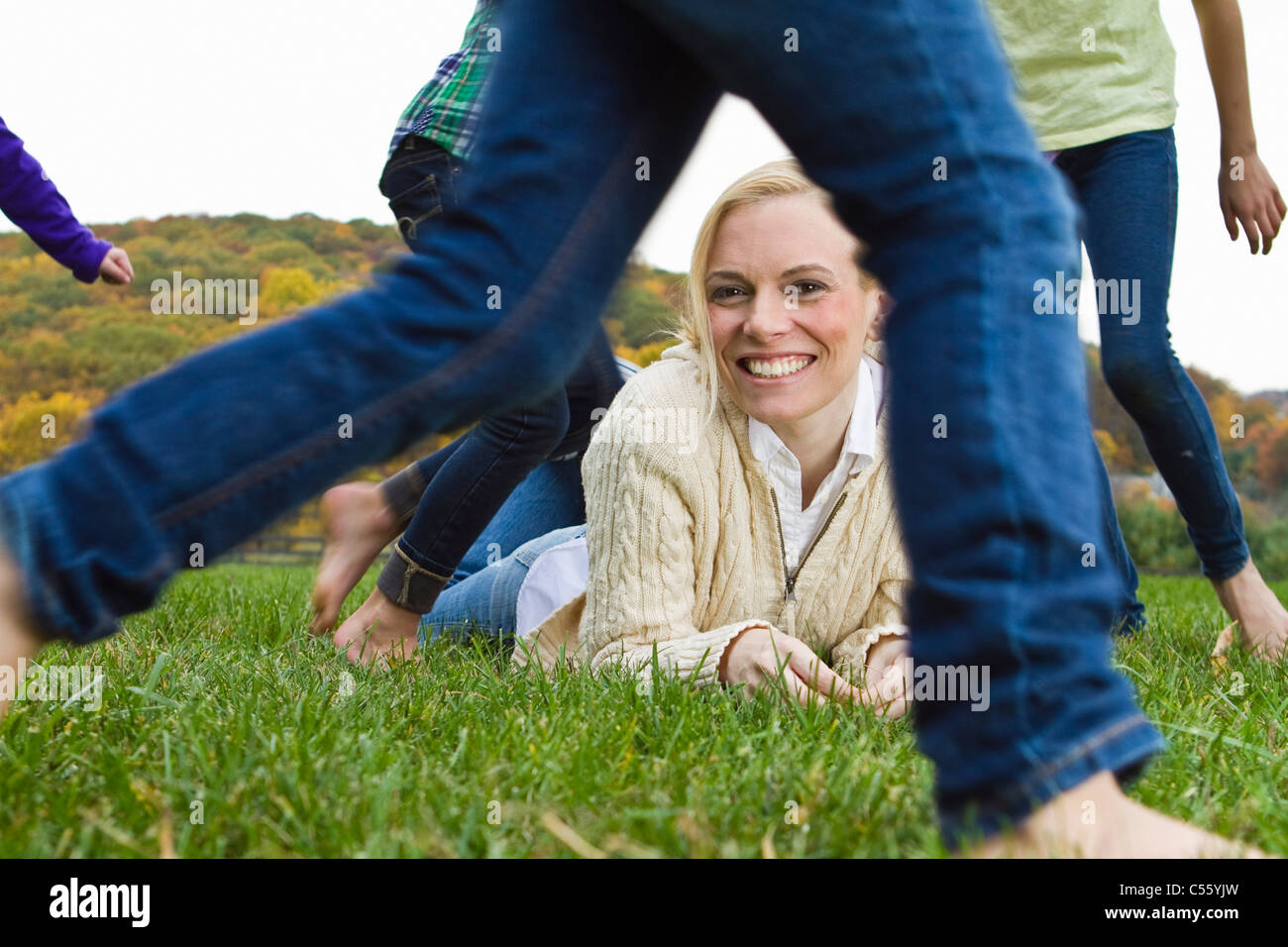 Portrait of woman lying on grass, people running around Stock Photo - Alamy