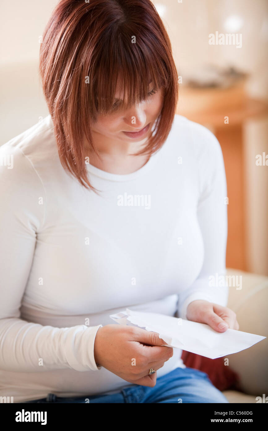 Attractive young woman opening an item of mail Stock Photo - Alamy