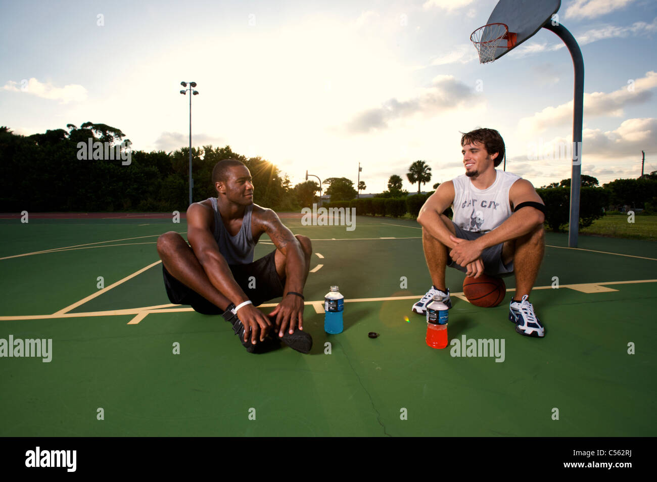 males resting, relaxing after after playing basketball on outdoor court ...