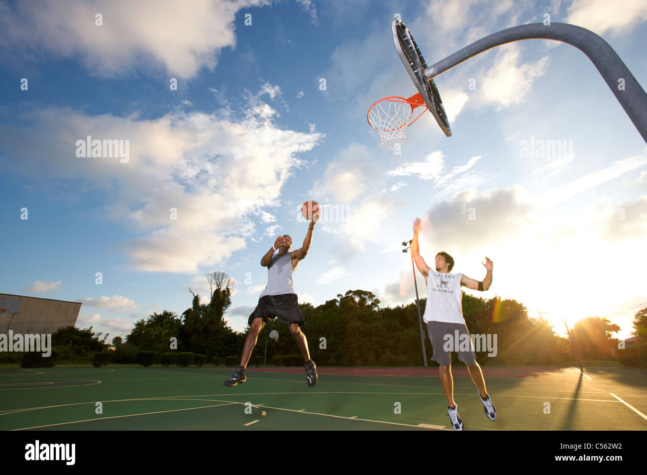 male scoring during outdoor basketball scrimmage between two young men ...
