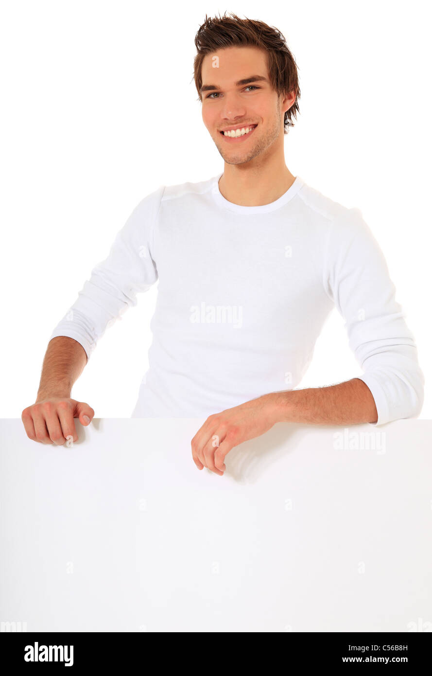 Attractive young man standing behind white wall. All on white ...