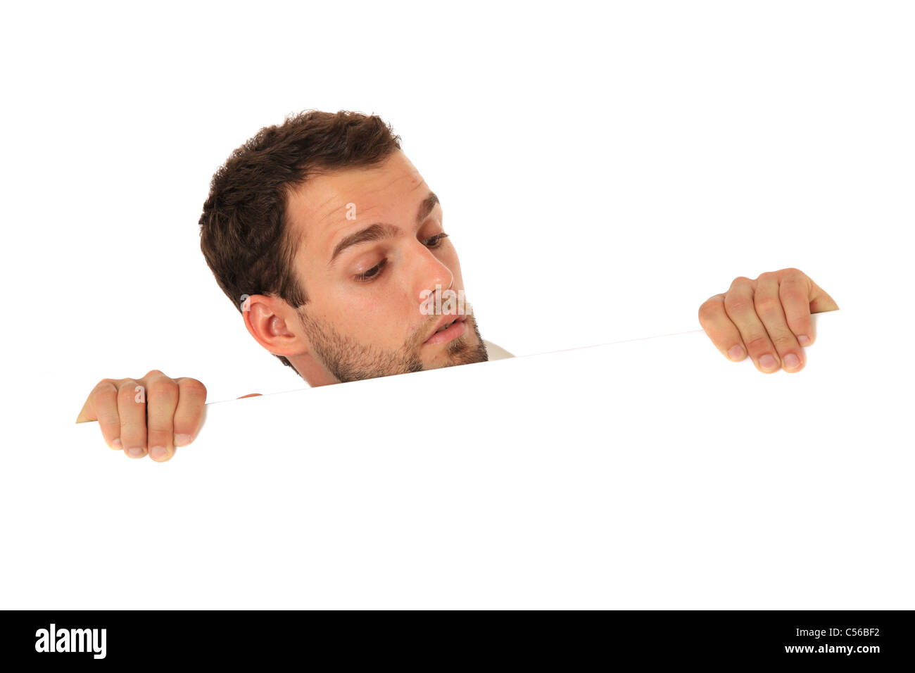 Attractive young guy standing behind white wall. All on white ...