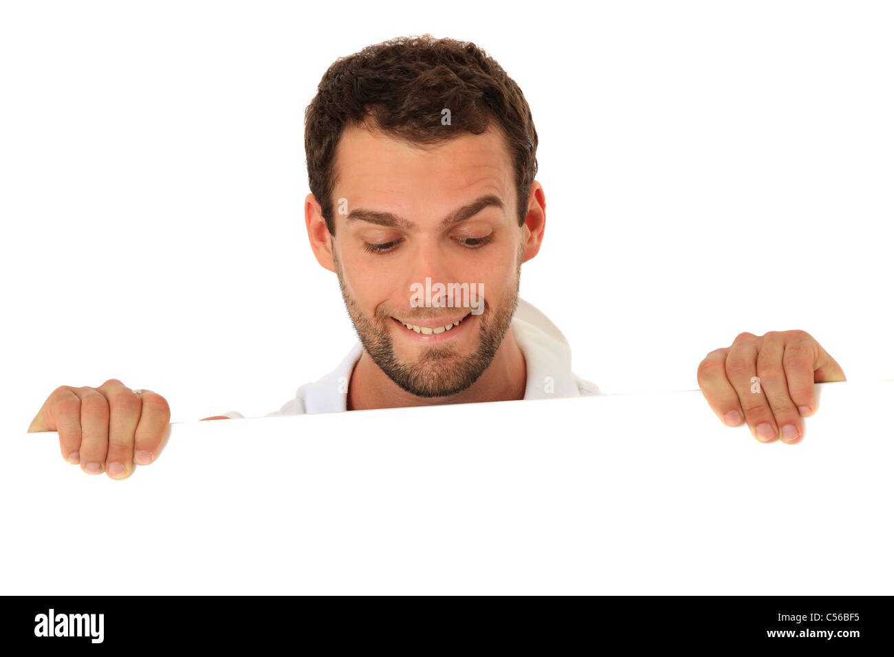 Attractive young guy standing behind white wall. All on white ...