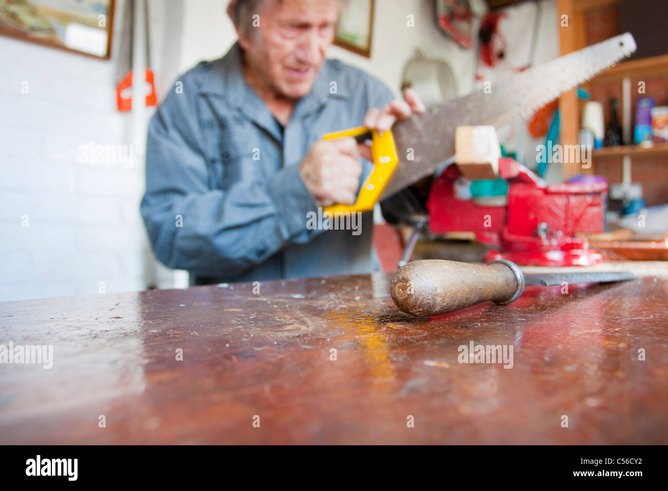 eldely retired man sawing in his workshop with focus on chisel in ...
