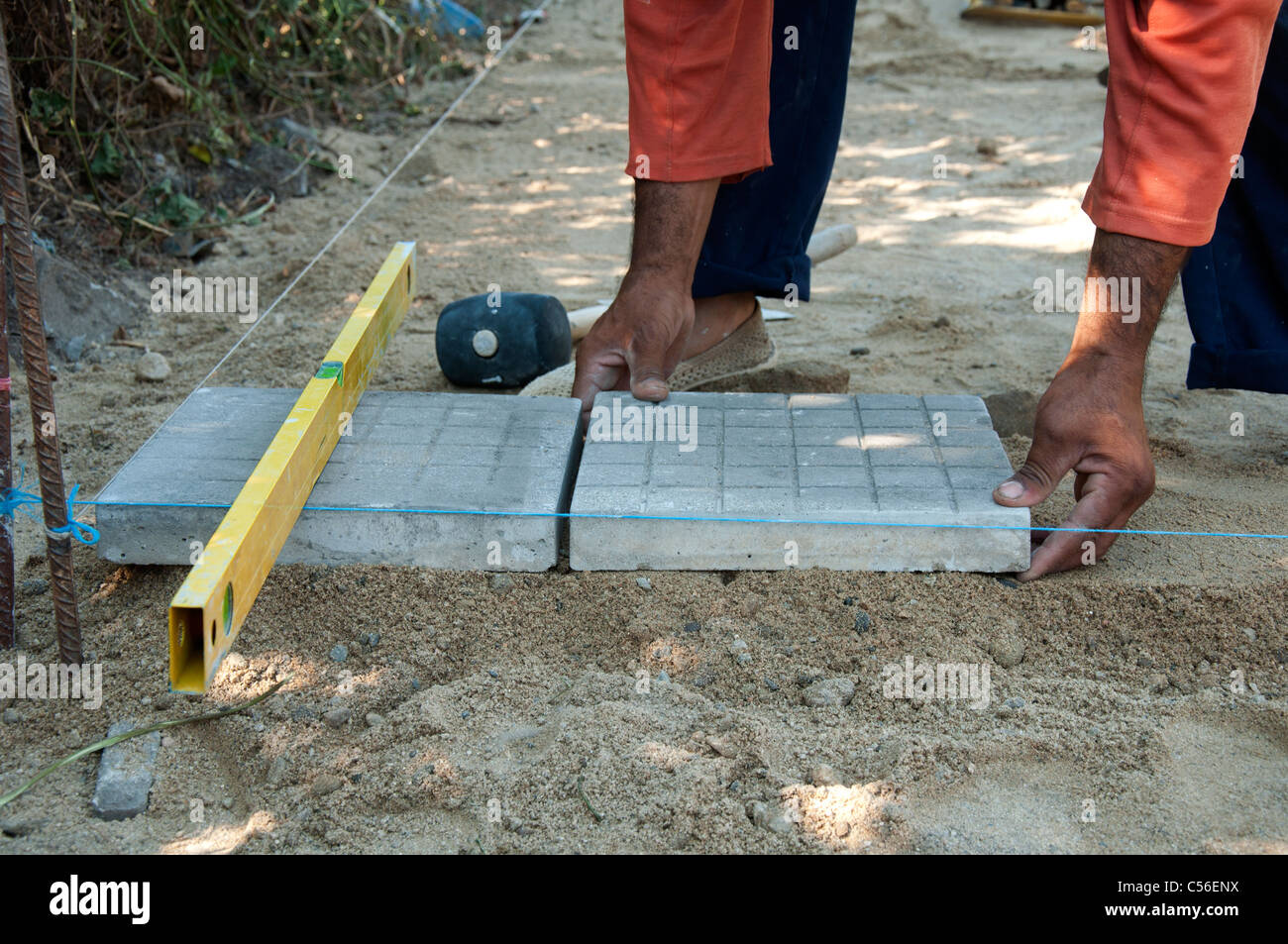 Worker puts sidewalk tiles. Walkway making Stock Photo - Alamy