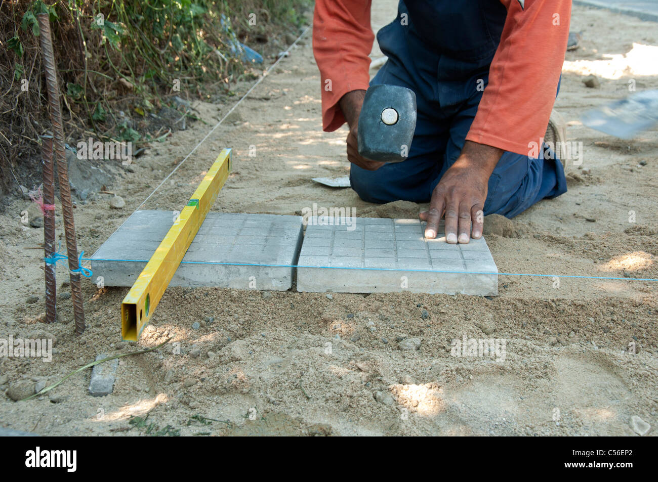Worker puts sidewalk tiles. Walkway making Stock Photo - Alamy