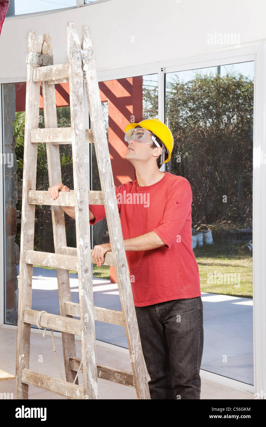 Engineer wearing helmet and eyegear and holding ladder Stock Photo - Alamy