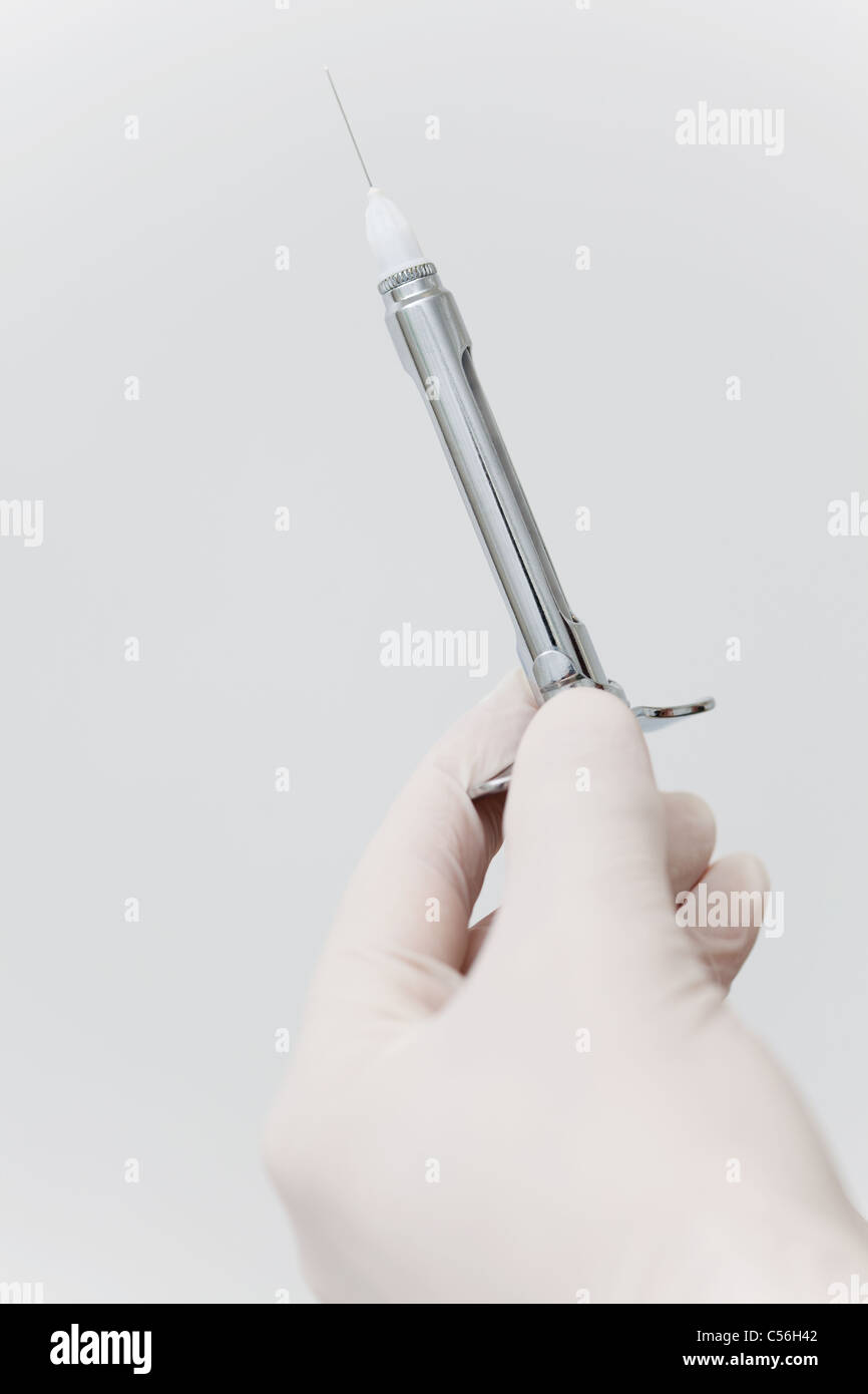 Close-up of human hand holding needle against white background Stock ...