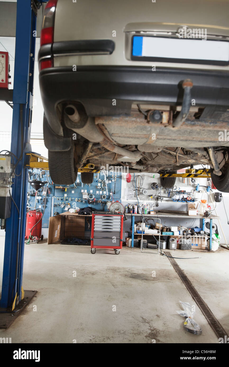 Car under repair on service lift in garage Stock Photo - Alamy