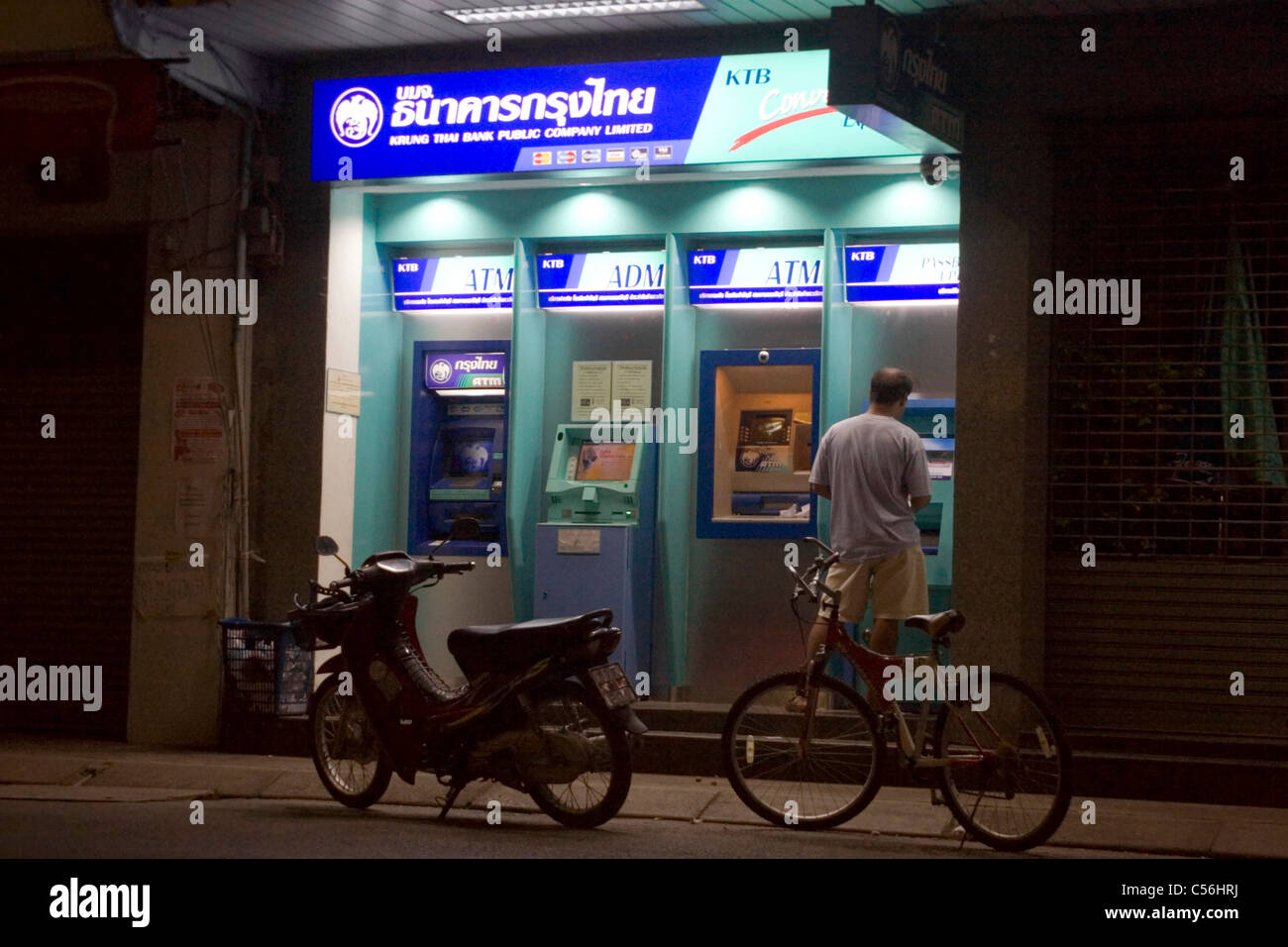 A man is using an ATM machine at night at a bank in a city in Northern ...