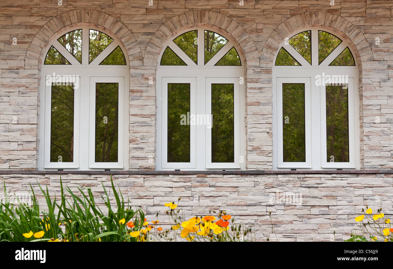 Three windows in the stone wall with a reflection of the forest Stock ...