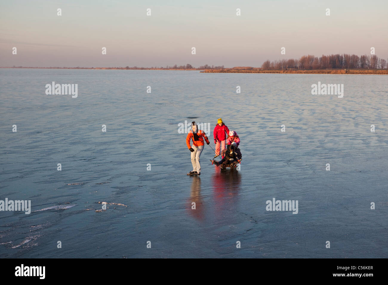 The Netherlands, Marken, Mother with children and sledge ice skating on ...