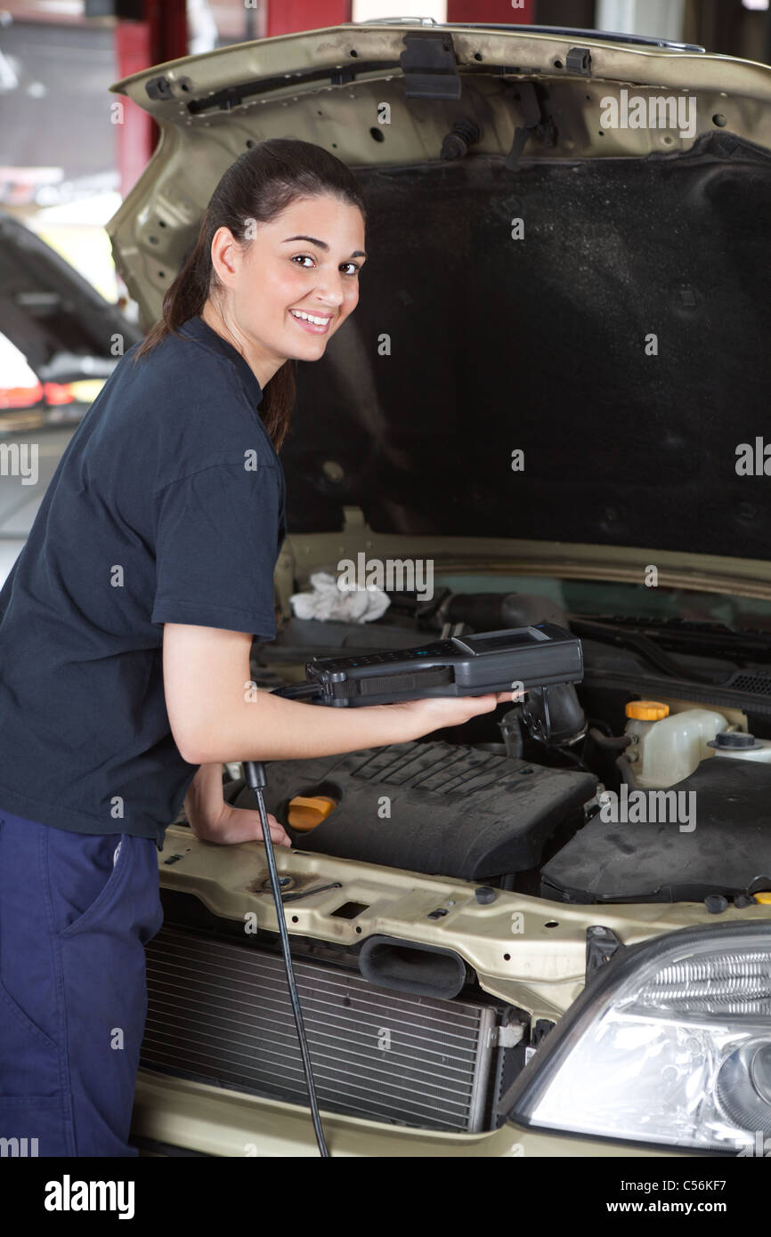 A happy female mechanic looking at the camera using a diagnostic scan ...