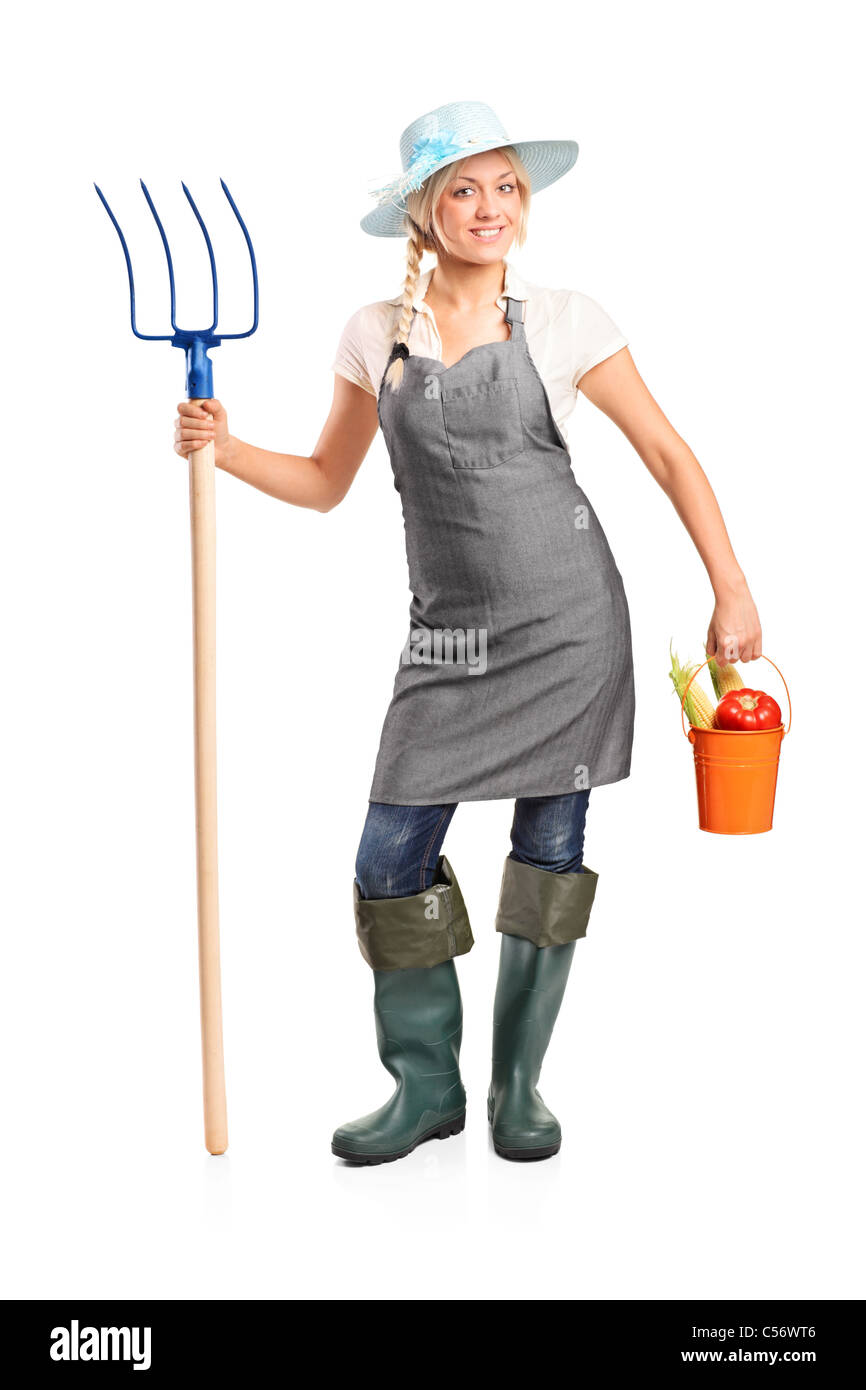 Full length portrait of a female farmer holding a pitchfork and bucket ...