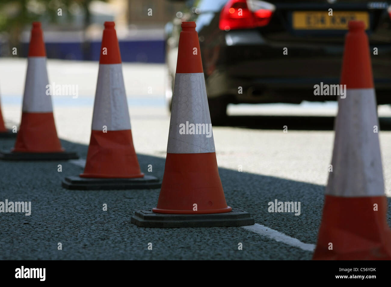 looking along a row of roadworks cones with a vehicle passing Stock ...